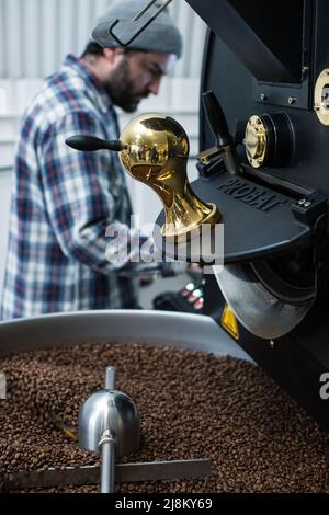 A coffee roaster checks coffee beans during roasting Stock Photo - Alamy
