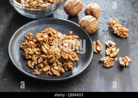 Peeled walnut kernels on plate on black table Stock Photo - Alamy