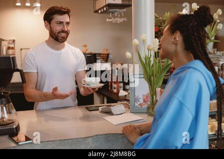 Man handing cup of tea to young woman sitting on bed Stock Photo - Alamy