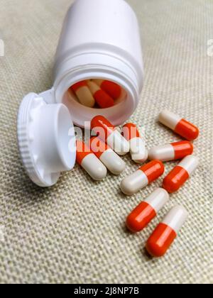 Medicinal capsules in gelatin shell spilled out of plastic jar. Medical ...