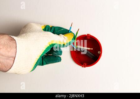 The hand touches uninsulated electrical wires that stick out of the ...