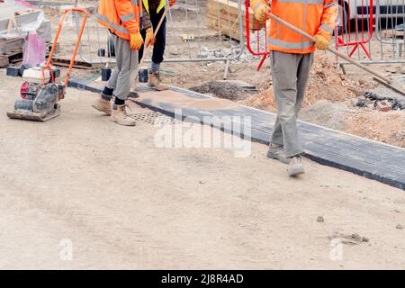 Paving stone workers filling joints of the block paved footpath with ...