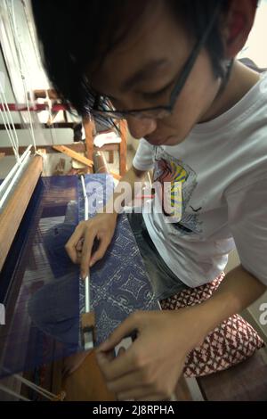 A worker finishing a songket fabric at Erika Rianti songket studio in ...