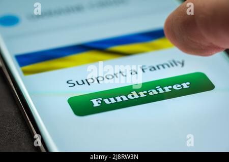Close-up finger pressing fundraiser button on smartphone screen ...