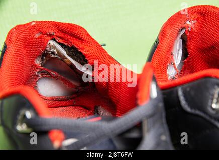 Old worn out ripped sneakers. Torn back in shoes, close-up. Shoe repair ...