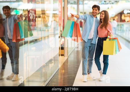 Buyers Couple Doing Shopping Pointing Finger Aside Posing In Mall Stock ...