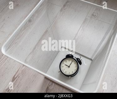 Top view of an alarm clock discarded in a white mesh metal trash bin ...