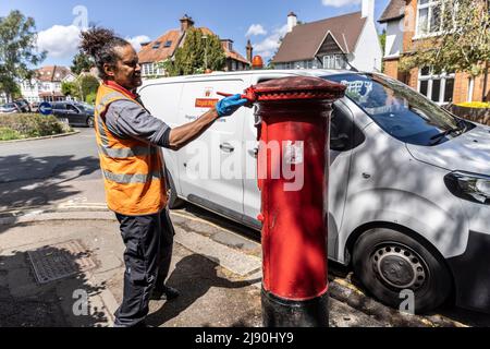 Royal Mail postal worker giving a post box a coat of red paint, London ...