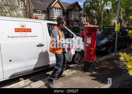 Royal Mail postal worker giving a post box a coat of red paint, London ...