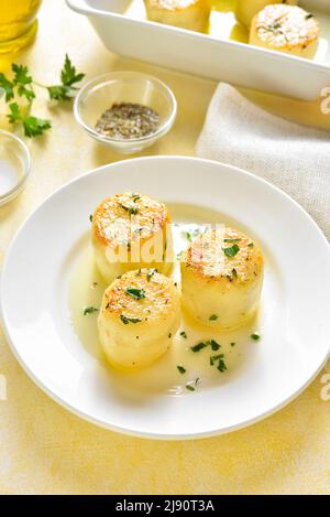 Close up view of fondant potatoes on plate over yellow background with ...