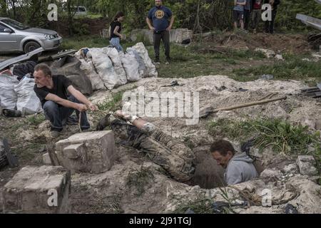 Malaya Rohan, Ukraine. 19th May, 2022. Men pull the bodies of two dead ...