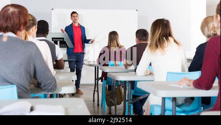 Teacher giving presentation to attentive students in modern classroom ...