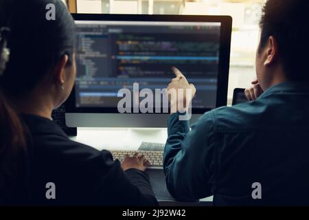 Software developers are analyzing about the code written into the program on the computer in ...