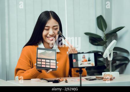 Young asian woman vlogging about cosmetics skin care items products on ...
