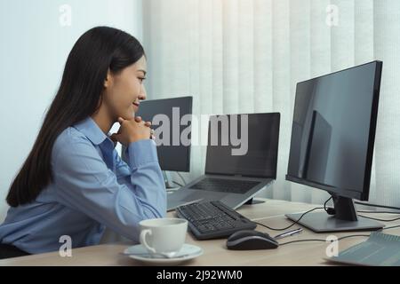 Asian woman software developers sitting in front of computers looking ...