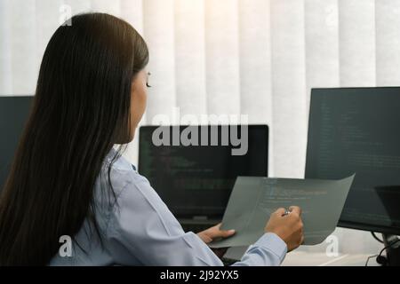 Asian woman software developers sitting in front of computers looking ...