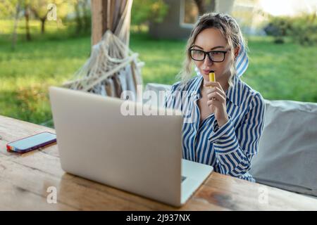freelance girl works at a computer and smokes an electrode cigarette ...