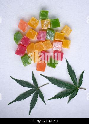 Layout of colorful marmalade and marijuana leaf on white textured ...