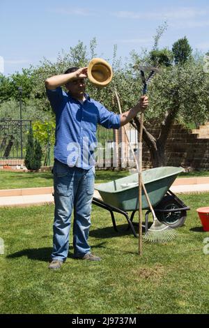 Image of a tired gardener who wipes sweat from his forehead in the ...