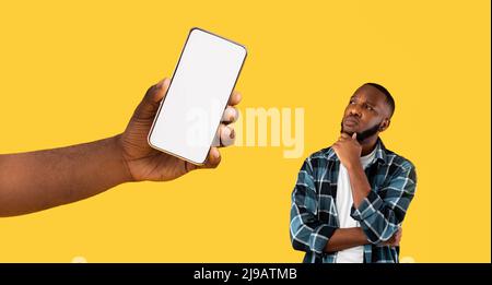 Pensive black guy looking at big white empty smartphone screen Stock ...