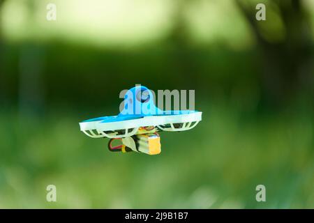 Small drone also race quad in blue, fly on brown wooden background ...