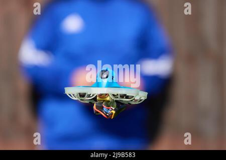 Small drone also race quad in blue, fly on brown wooden background ...