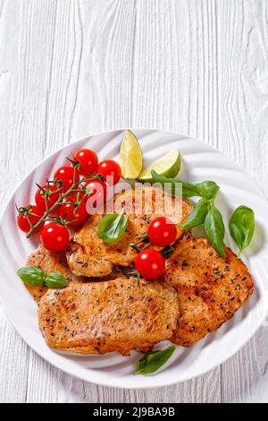 tomato basil pesto pork cutlets with fresh tomatoes, lime wedges and ...