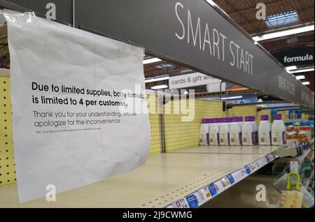A sign hangs on the empty shelves of a refrigerated cases used to ...