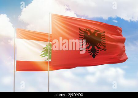 Lebanon and Albania flags waving together in the wind on blue cloudy ...