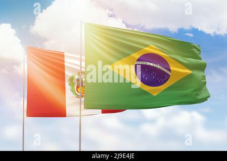 Peru and Brazil flags waving together in the wind on blue cloudy sky ...