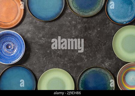 Many color empty ceramic plate on black background, close up. Stacked ...