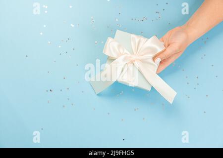 Flat lay of women's hands holding a gift wrapped and decorated with a ...