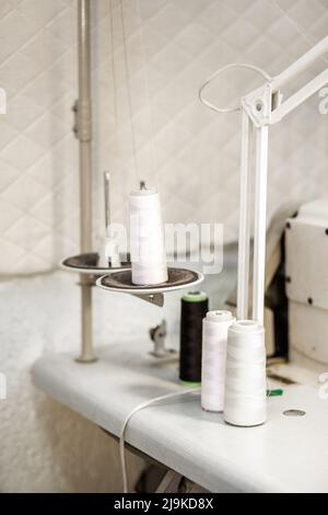 Reels with white threads for a sewing machine on a polished wooden ...