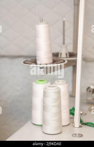 Reels with white threads for a sewing machine on a polished wooden ...