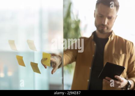 Manager pointing to a glass Board with sticky notes Stock Photo - Alamy