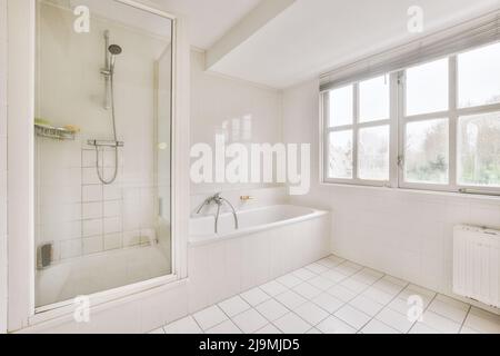 White ceramic tub placed near shower at mosaic wall in light spacious ...