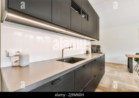 Sink and tap installed on counter under black cupboards inside ...