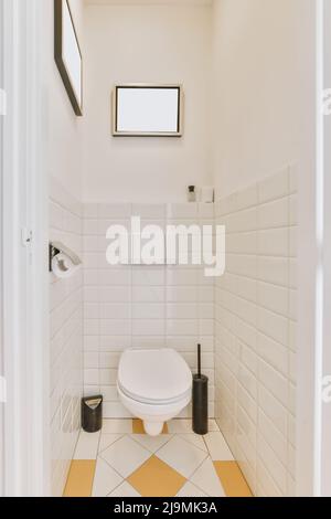 White ceramic toilet placed at white tiled wall in light stylish ...