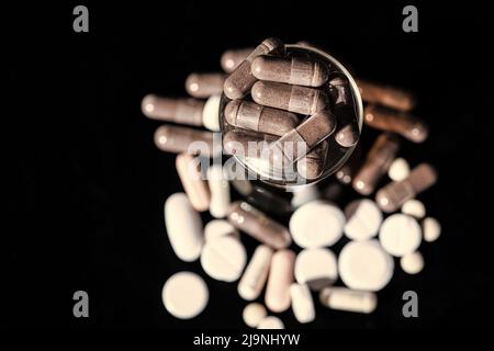 Starch capsules gel caps medication in glass dark background, caplets ...