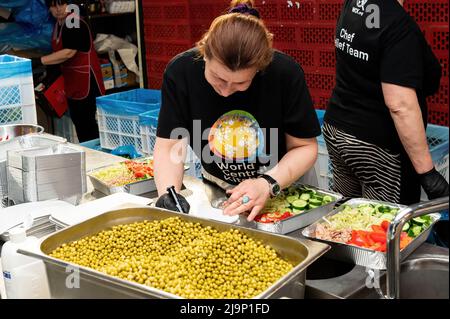 A volunteer at a World Central Kitchen location prepares food, (meals ...