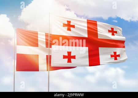 Denmark and Georgia flags waving together on blue cloudy sky, two ...