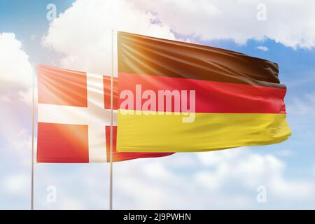 Germany and Denmark flags waving together on blue cloudy sky, two ...