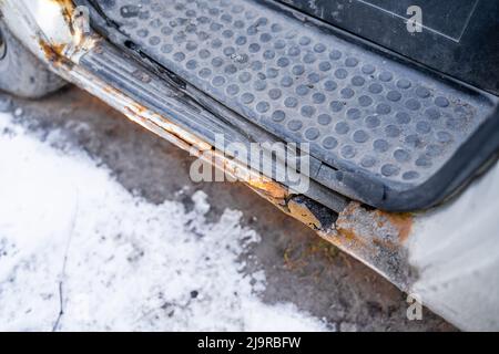Rusty driver's door sills. Corrosion of the body of a red old car after ...