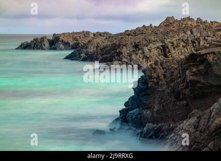 Lava rocks along tranquil shoreline of San Cristobal Island, Galapagos ...