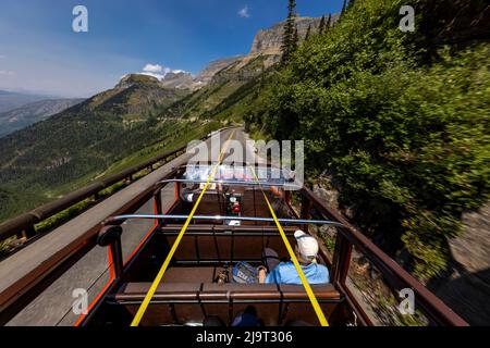 Iconic Red Jammer bus in motion in Glacier National Park, Montana, USA ...