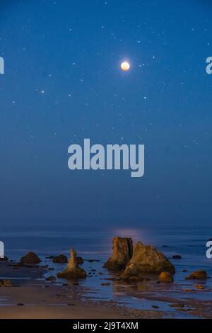 USA, Oregon, Bandon Beach. Lunar eclipse reflects on ocean shore at ...
