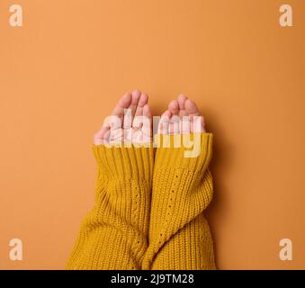 Two female hands folded palm to palm on an orange background, top view ...