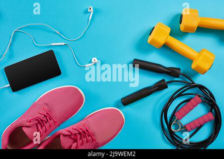 Flat lay shot of sneakers, jumping rope, dumbbells and smartphone on ...