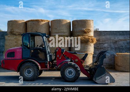 Farmer unloading round bales of straw with a front end loader Storing ...