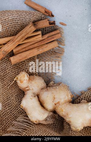 Whole cinnamon sticks on mottled grey surface with burlap and copy ...